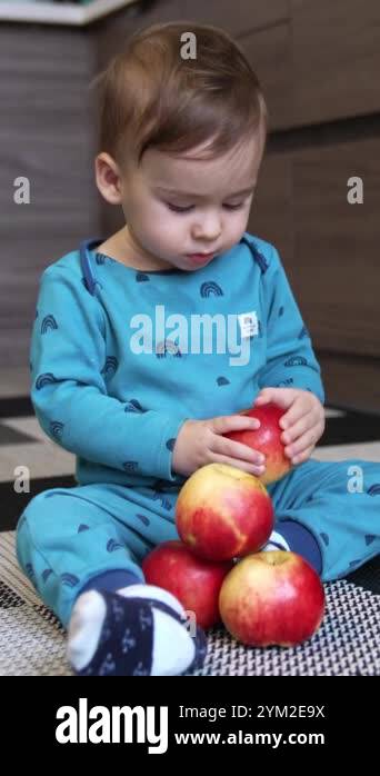 Focused baby boy looking at the apples in front of him. Adorable ...