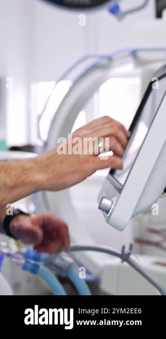 Male doctor standing near the screen of lung ventilation machine ...