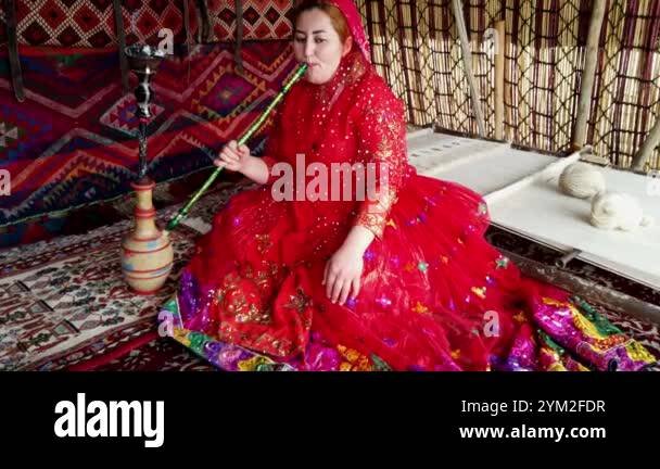 Qashqai woman in traditional red dress is sitting cross legged on the ...