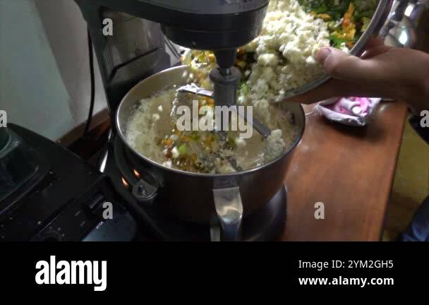 Chef adding ingredients to a stand mixer for preparing authentic tamale ...