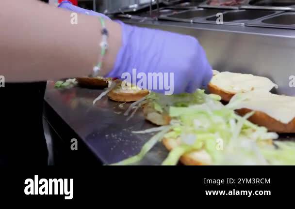 A cook in a fast food restaurant puts vegetables, including cabbage and ...