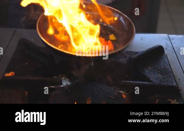 Unrecognizable chef cooking tasty flambe style dish on pan in modern ...
