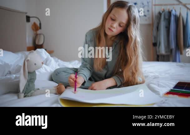 Creative girl doing arts sitting white mattress indoors. Cute child ...
