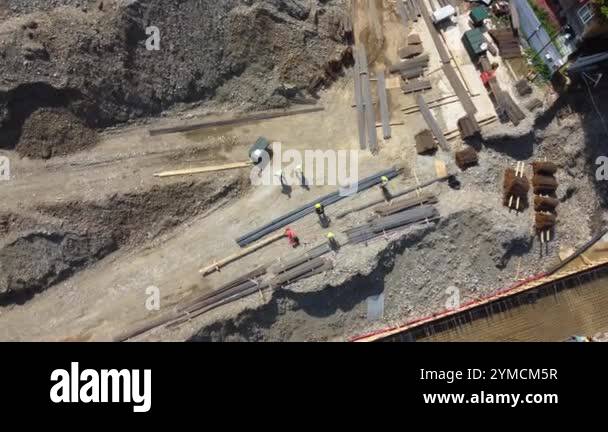 Construction workers carry and move long steel bars under sunny skies ...