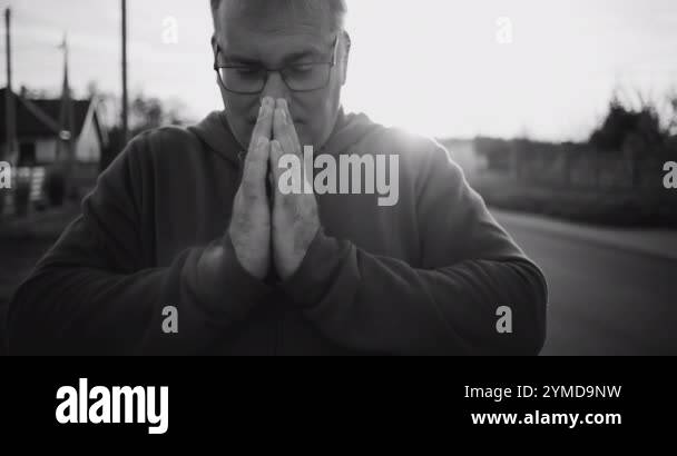 Man with hands clasped in prayer, head bowed, contemplative expression ...