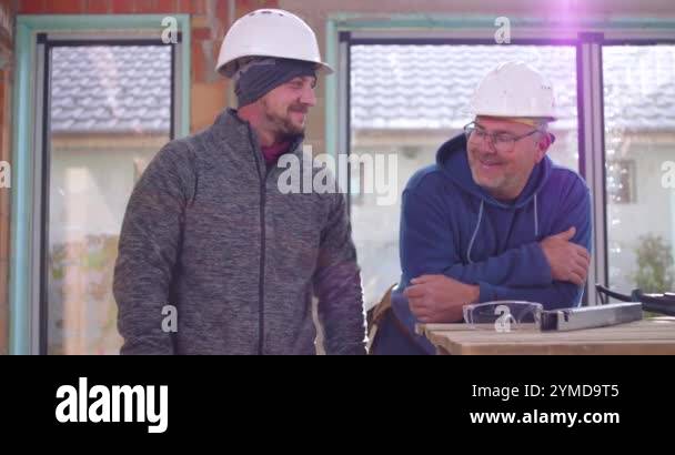 Two construction workers sharing a laugh at workbench, teamwork and ...