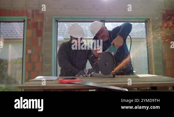 Construction workers using electric grinder tool on metal, producing ...