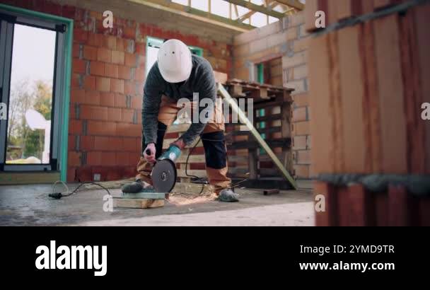 Construction worker operating angle grinder, sparks flying from metal ...