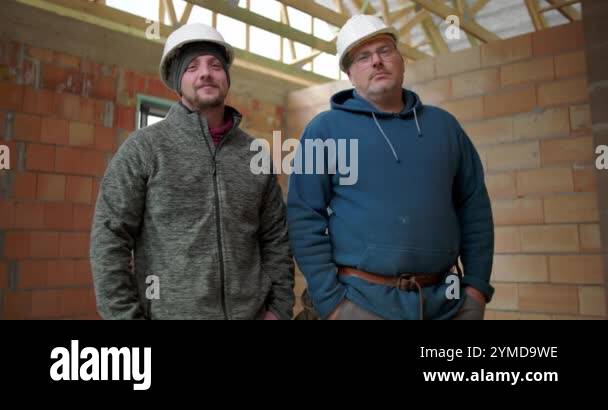 Construction workers standing indoors, confident poses, two men in ...
