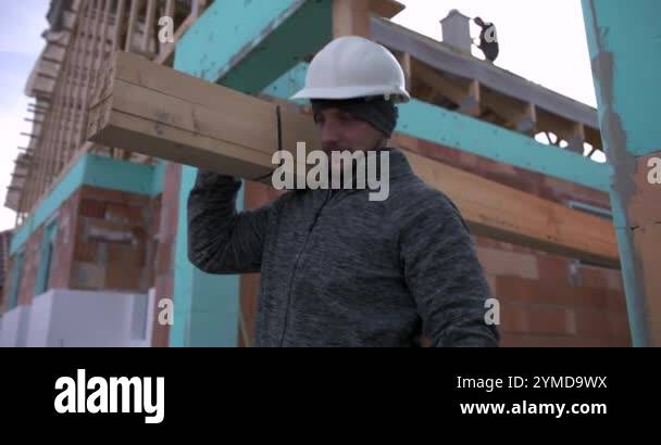 Carpenters carrying long wooden beams at construction site, teamwork in house building project ...