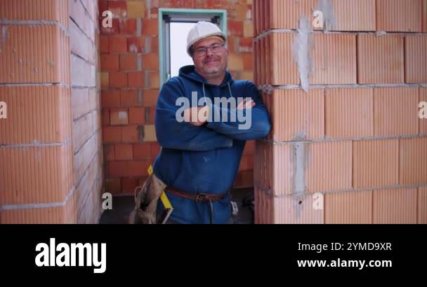 Construction worker leaning against brick wall in building under ...