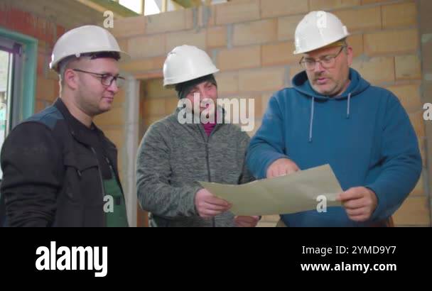 Construction workers discussing building plans on-site, team ...
