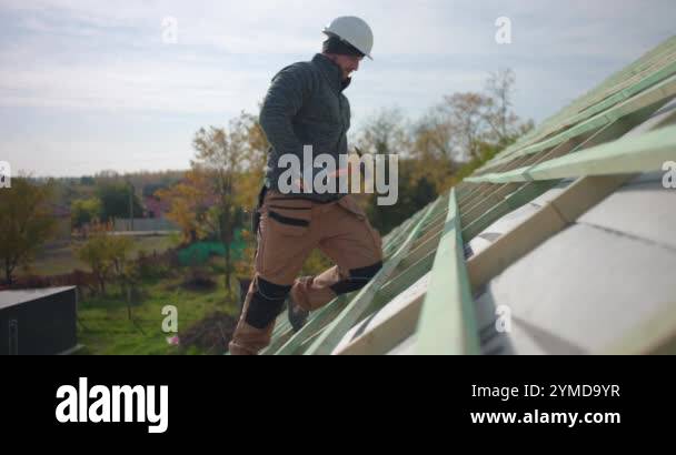 Construction worker hammering roof beams on building structure, wearing ...