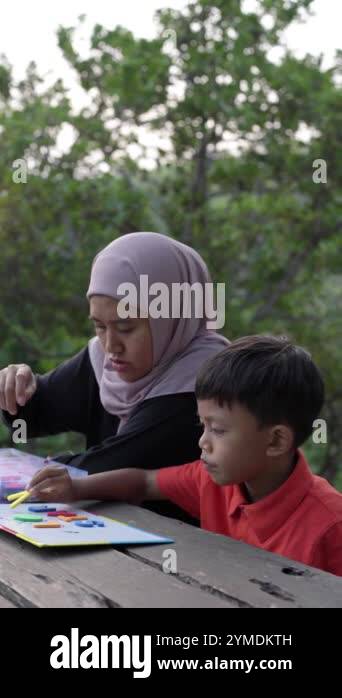 Indonesian mom in hijab and her son learn how to arrange letters in the ...