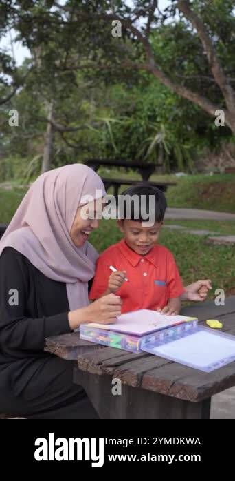 Indonesian mom in hijab and her son learn how to arrange letters in the ...
