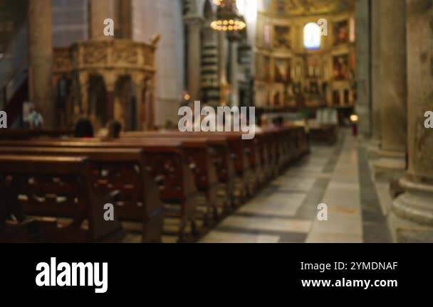 Blurry interior of a grand, historic church with long wooden pews ...