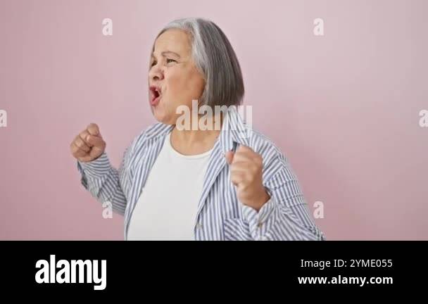 Frustrated middle-aged woman, grey-haired and standing over a pink ...