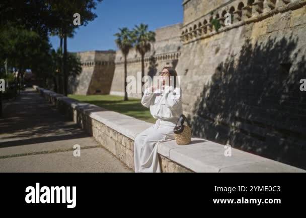 A beautiful hispanic woman enjoys the sunny day sitting by the historic ...