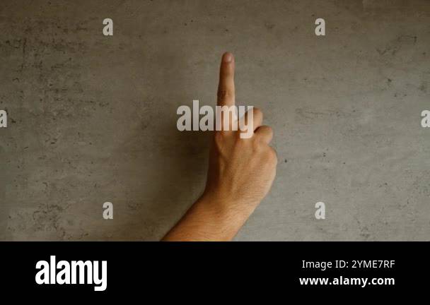 Man's hand pointing upward with index finger against rough concrete ...