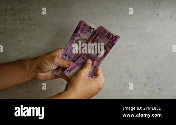 Hands counting philippine pesos against a concrete background ...