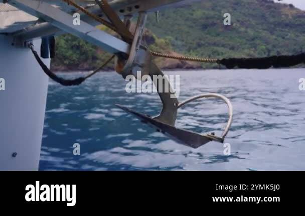 A close-up shot shows a metal anchor, attached to a chain with a ...