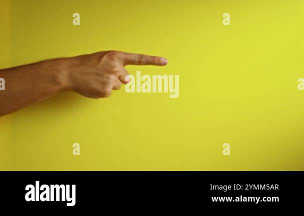 Hand pointing on a bright yellow background with the index finger ...