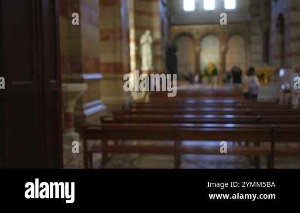 Blurry interior of a church with wooden pews, stone columns, bokeh ...