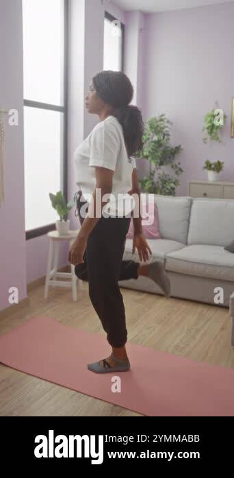 African american woman exercises indoors in her living room, standing ...