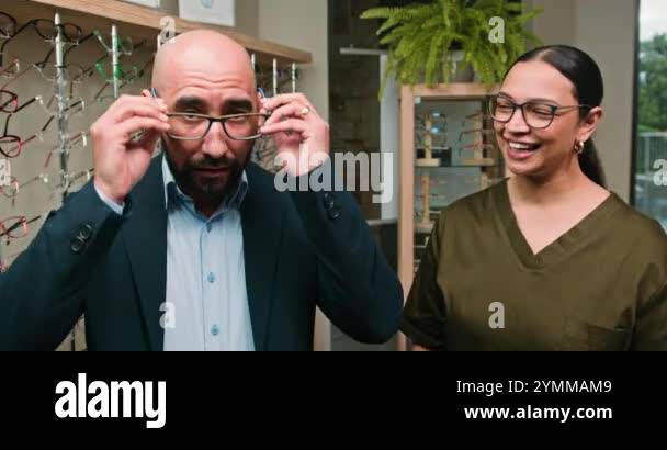 A man tries on new eyeglasses at an optometrists office. The ...