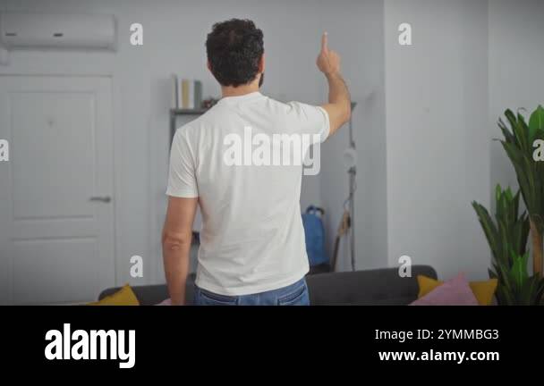 Handsome middle age man, posing backwards at home, wearing white t ...