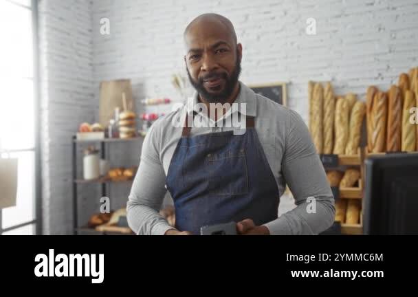 Handsome man with beard and bald head in bakery holding payment ...