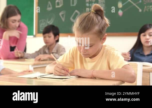 Caucasian smart child smiling at camera while doing classwork at ...