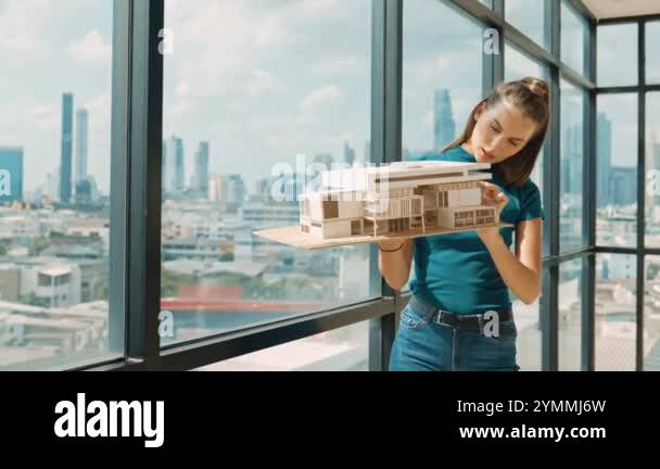 Young happy beautiful engineer check house model by turning left side ...