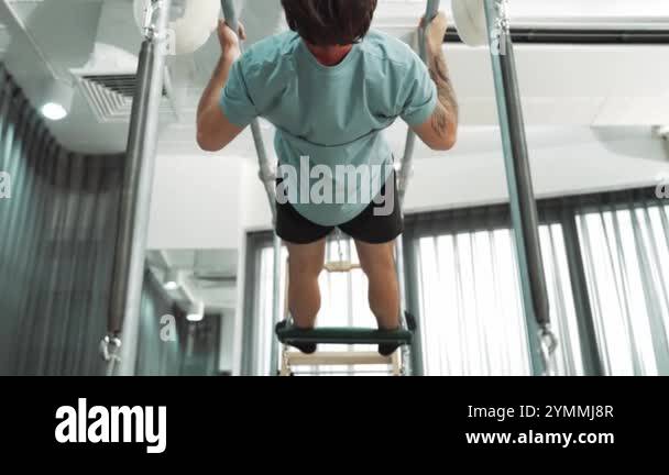 Man gripping bar on pilates trapeze table for core strength and upper ...