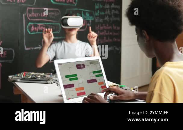 African boy programming system while caucasian girl enter metaverse while sitting at blackboard ...