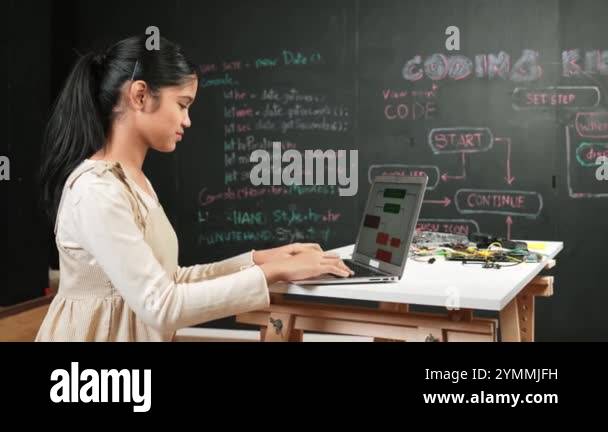 high school girl writing code or engineering prompt while attend in STEM technology class ...