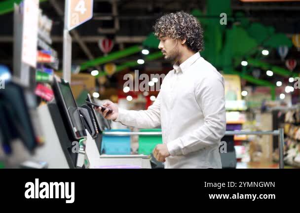 Male customer using self-service cashier checkout in a supermarket ...