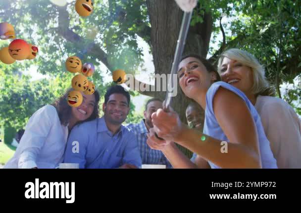 Smiling friends at picnic table with floating emoji animation over them ...