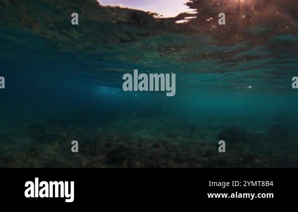 Ocean wave breaks over the reef bottom. Underwater view of a surfing ...
