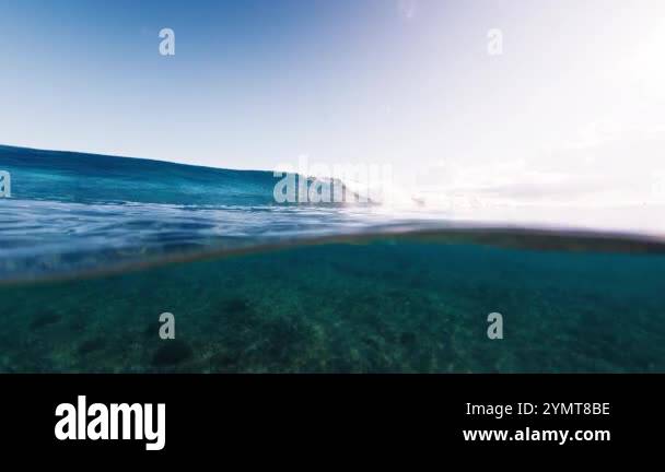 Ocean wave breaks over the reef bottom. Underwater view of a surfing ...