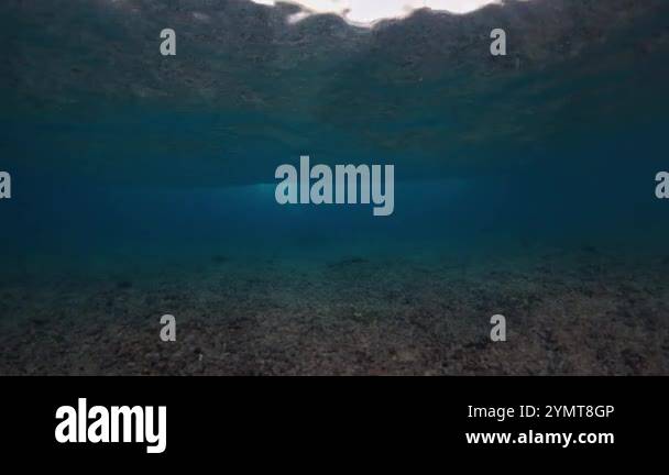 Ocean wave breaks over the reef bottom. Underwater view of a surfing ...