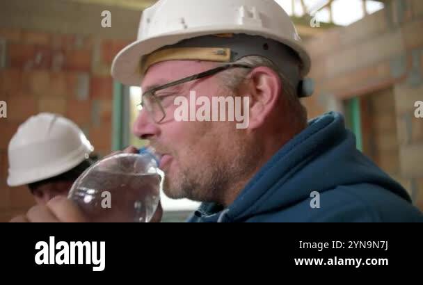 Construction worker drinking water during a break, staying hydrated ...