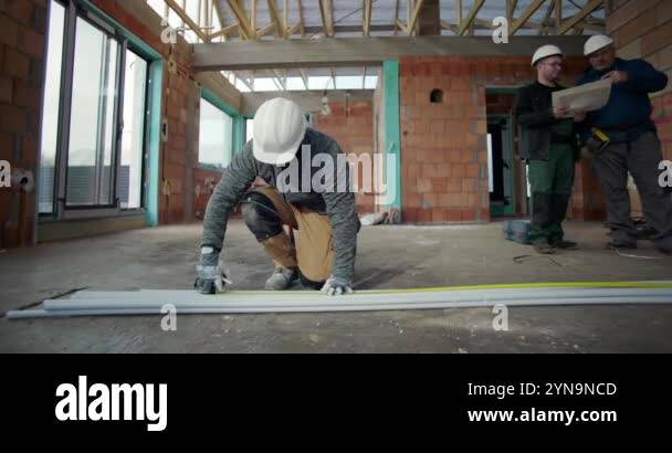 Construction worker measuring PVC pipes on the floor in unfinished ...
