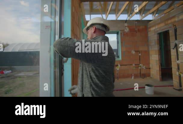 Construction worker checking window alignment and condition during ...