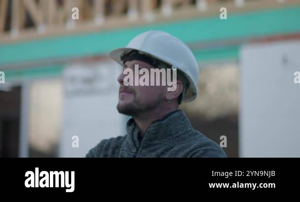 Construction worker in hard hat, looking upward thoughtfully at ...