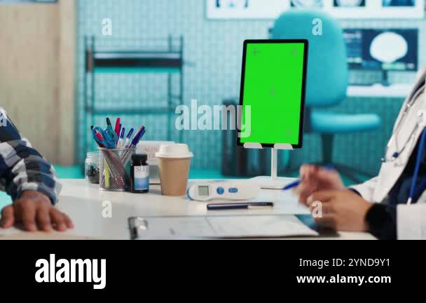 Female general practitioner and patient looking at green screen on ...