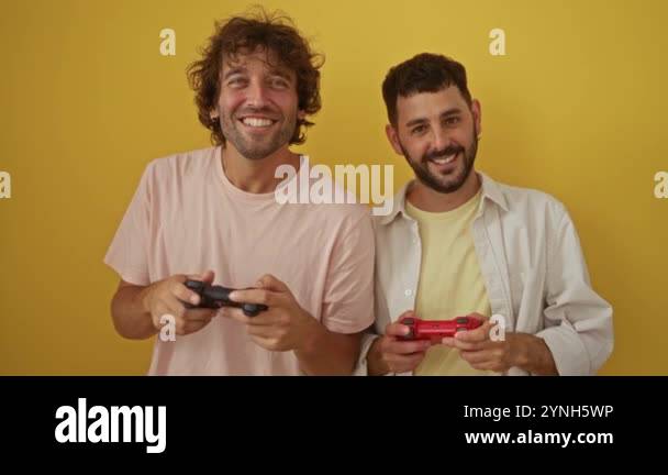 Two men playing video games with controllers, standing together against ...