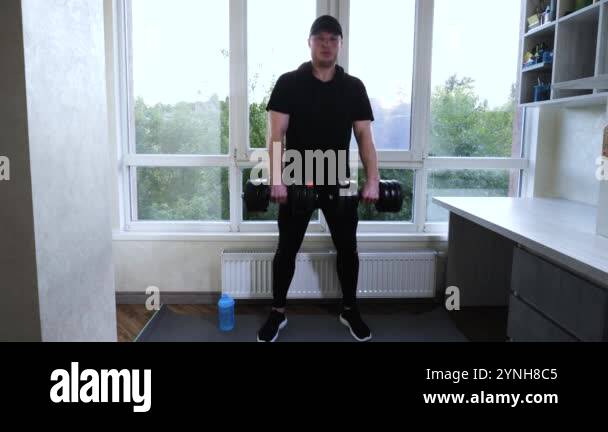 An athlete performs a leg squat exercise with dumbbells in his hands ...