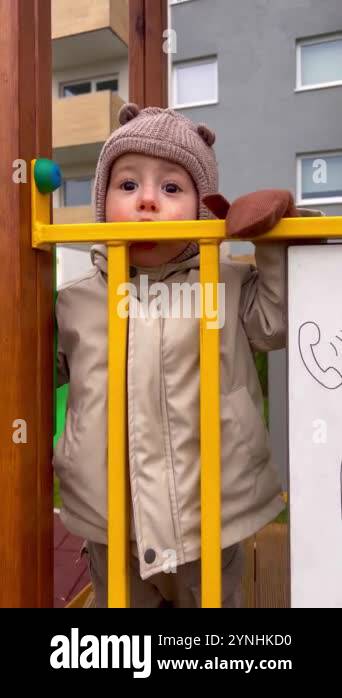 A child with brown eyes and wearing a beige jacket and cap touches an ...
