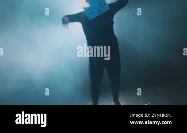 A person in a dark setting poses with a drawing covering their face ...